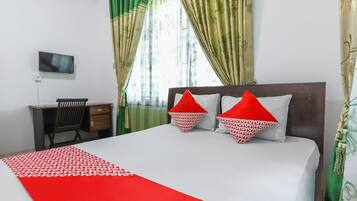 Quarto de hotel com cama, escrivaninha e televisão.