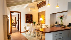 Cozinha moderna com ilha central, área de jantar com mesa e cadeiras, e parede de tijolos decorativa.