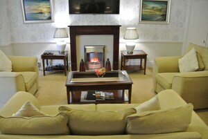 Uma sala de estar com lareira, duas luminárias e uma TV fixada na parede.