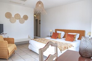 Quarto com cama, cadeira, mesa, abajur e luminária pendente.
