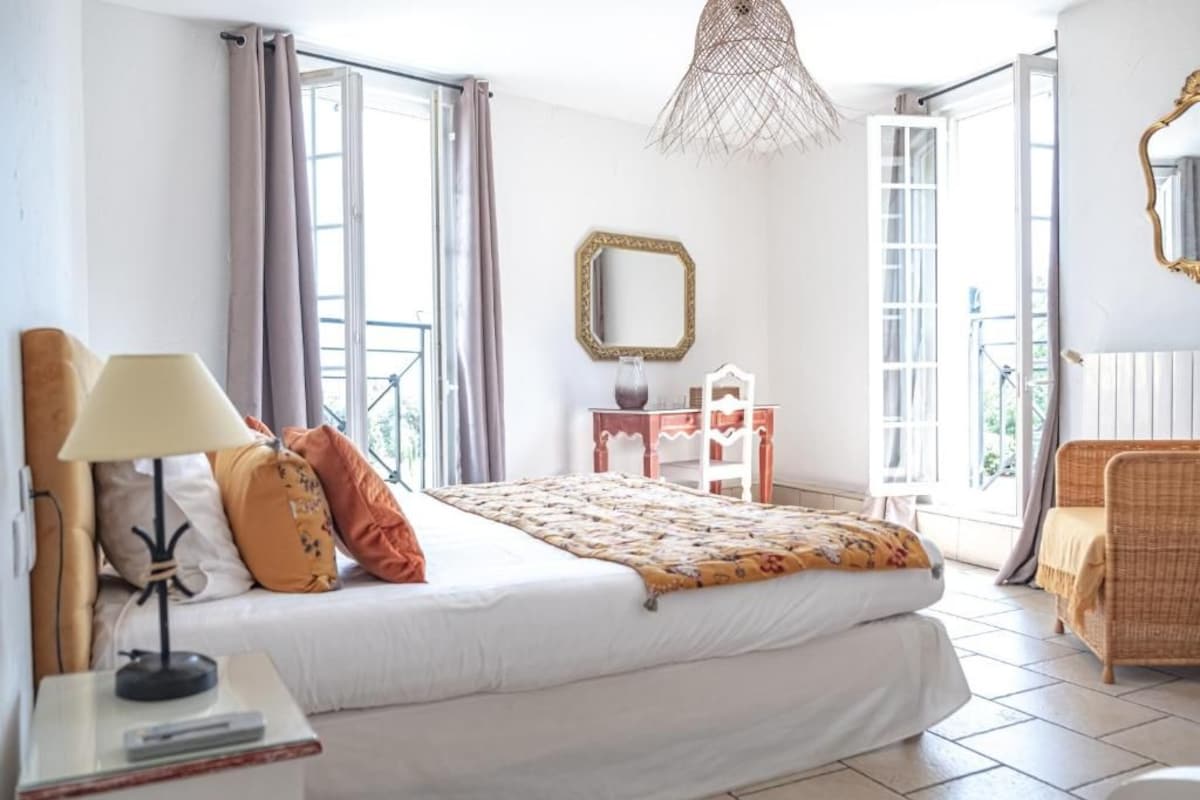 Quarto com cama, luminária, cômoda, espelho e cadeira.