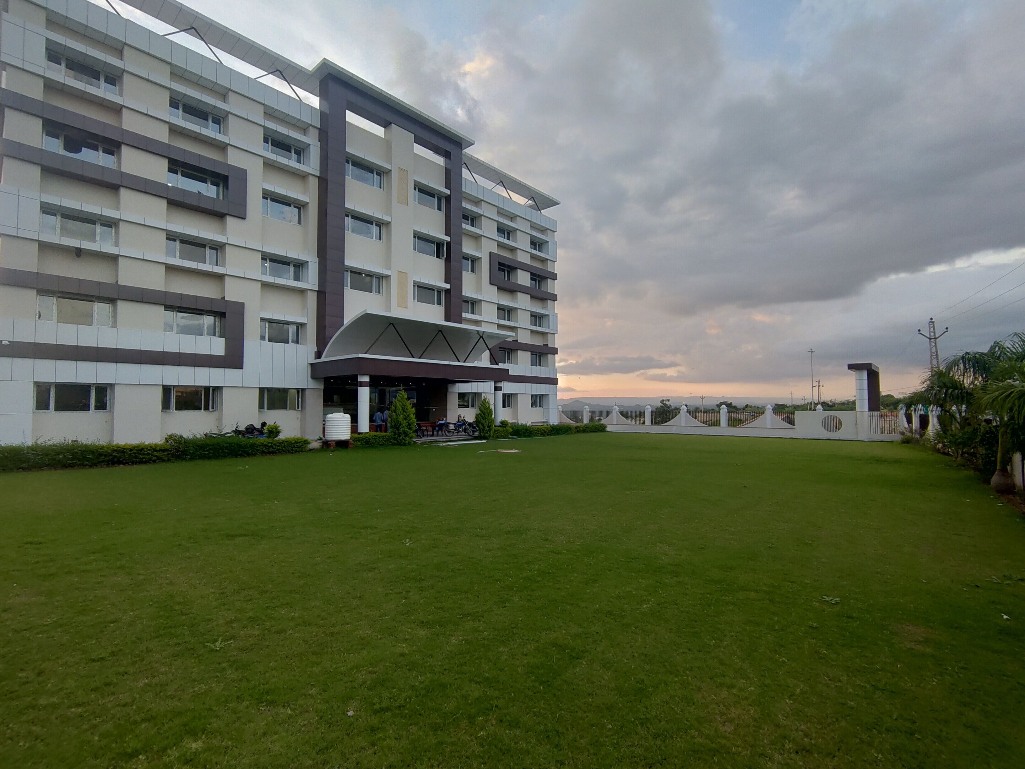 Um hotel com vários andares, teto plano e um amplo pátio gramado.