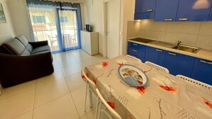 Um espaço compacto com área de refeições, cozinha compacta e sofá.