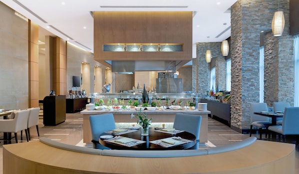 Um restaurante moderno com bar central, área de estar e buffet.