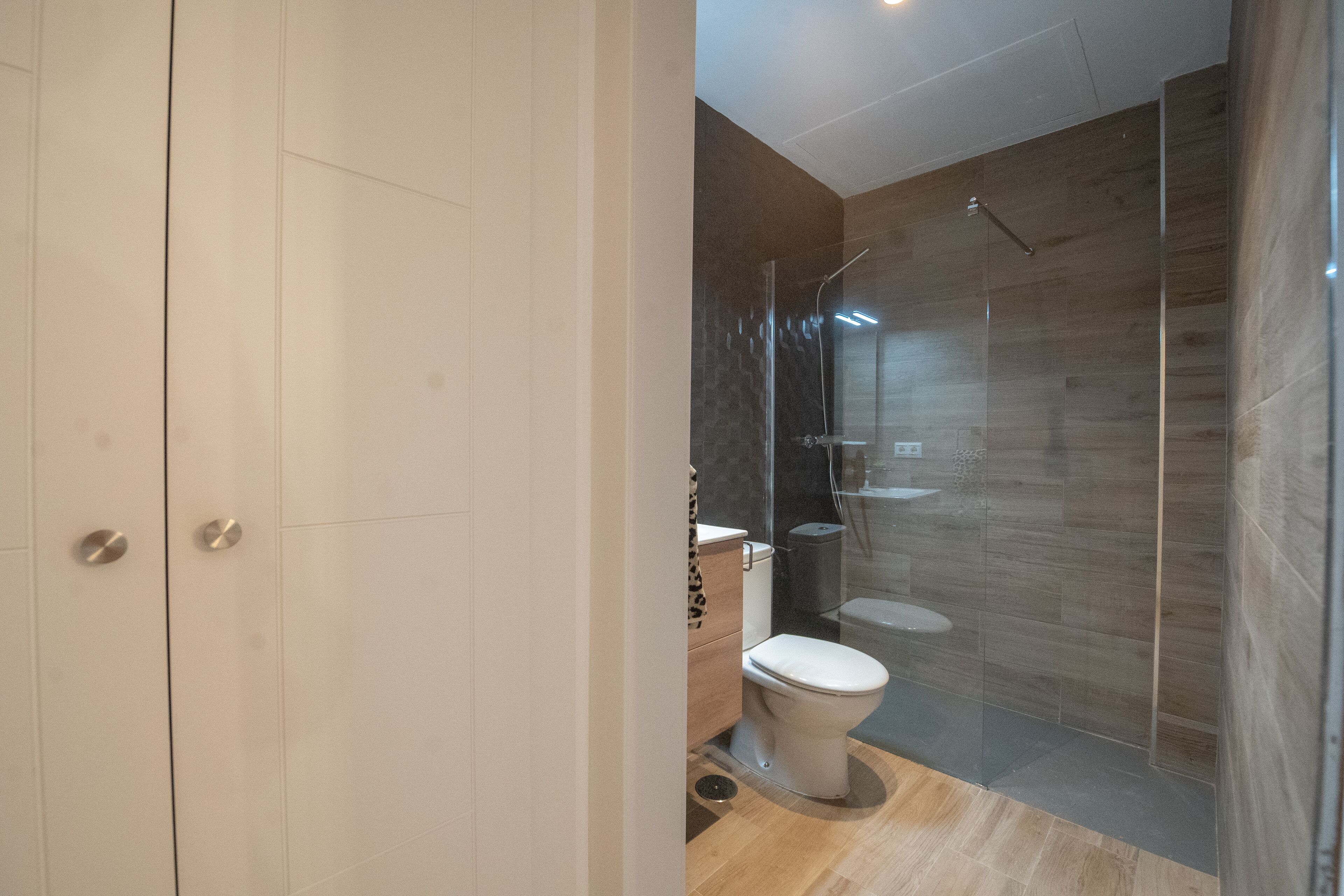 Uma casa de banho moderna com cabine de duche em vidro, sanita e lavatório.