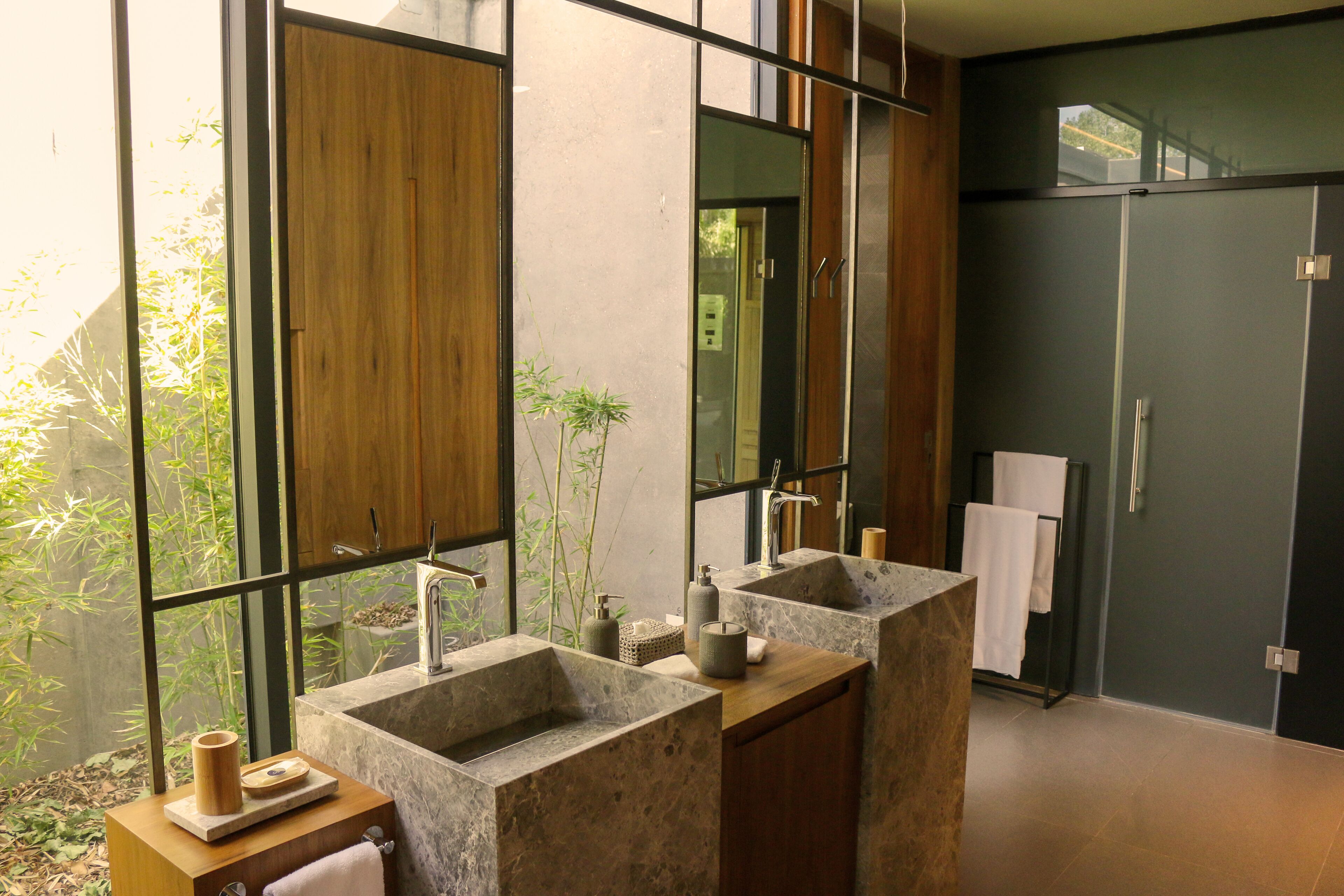 Casa de banho moderna com duas pias, um espelho grande e vista para o verde lá fora.