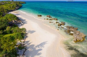Na praia, praia de areia branca, espreguiçadeiras, guarda-sóis de praia 