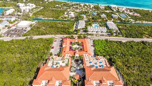 Vista aérea de um resort com vários edifícios, piscina e praia.