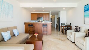 Uma sala de estar moderna com um sofá, mesa de centro e uma área de cozinha ao fundo.