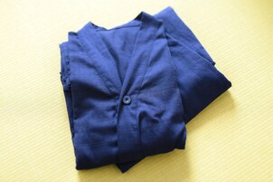 Uma camisa azul bem dobrada sobre uma superfície amarela com textura.