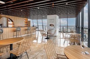 Uma cafeteria moderna com detalhes em madeira, um balcão e vista para a cidade.