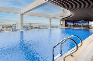 Uma grande piscina interna com vista para a paisagem urbana, teto curvo e um mural na parede.