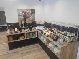 Buffet de café da manhã com diversos alimentos e recipientes.