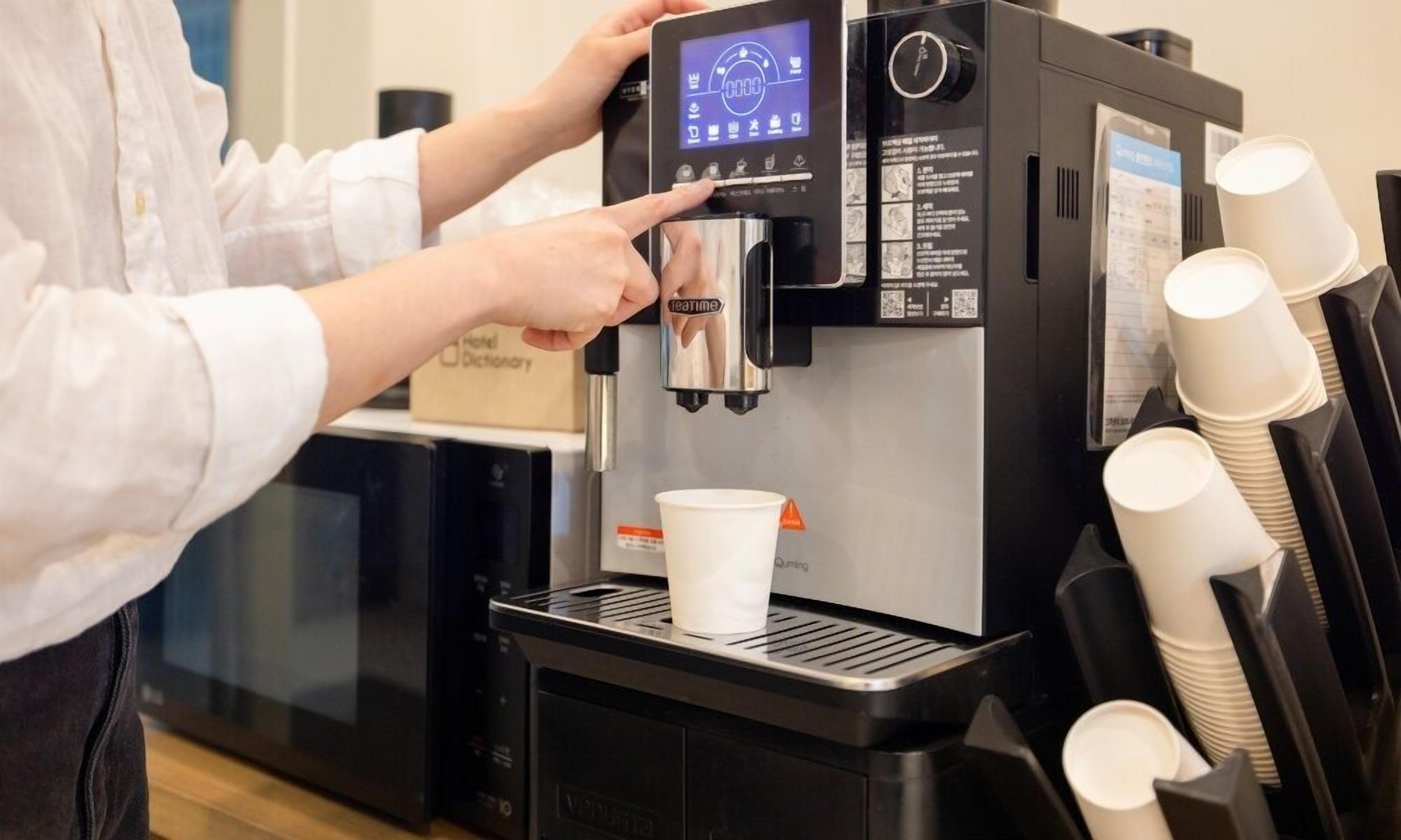 Máquina de café com visor digital e uma chávena colocada abaixo.