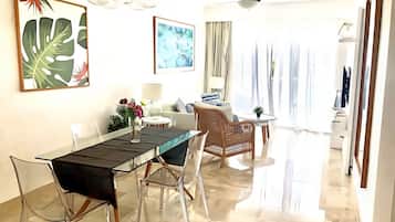 Uma sala de estar moderna com área de jantar, ventilador de teto e vista através de janelas amplas.