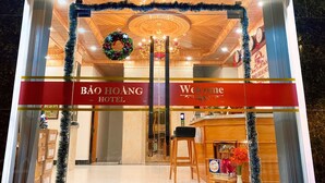 Entrada do Hotel Bảo Hoàng, com uma faixa vermelha, um candelabro e uma coroa de Natal.