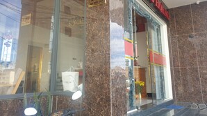 Entrada de hotel com fachada de mármore, vitrine visível e decoração de árvore de Natal.