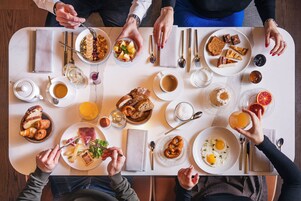 Uma mesa de café da manhã com diversos pratos, talheres e utensílios.