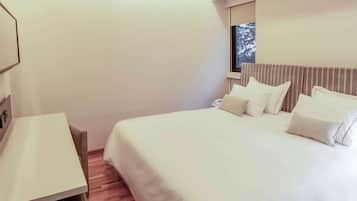 Quarto de hotel com uma cama, mesa de cabeceira e janela.