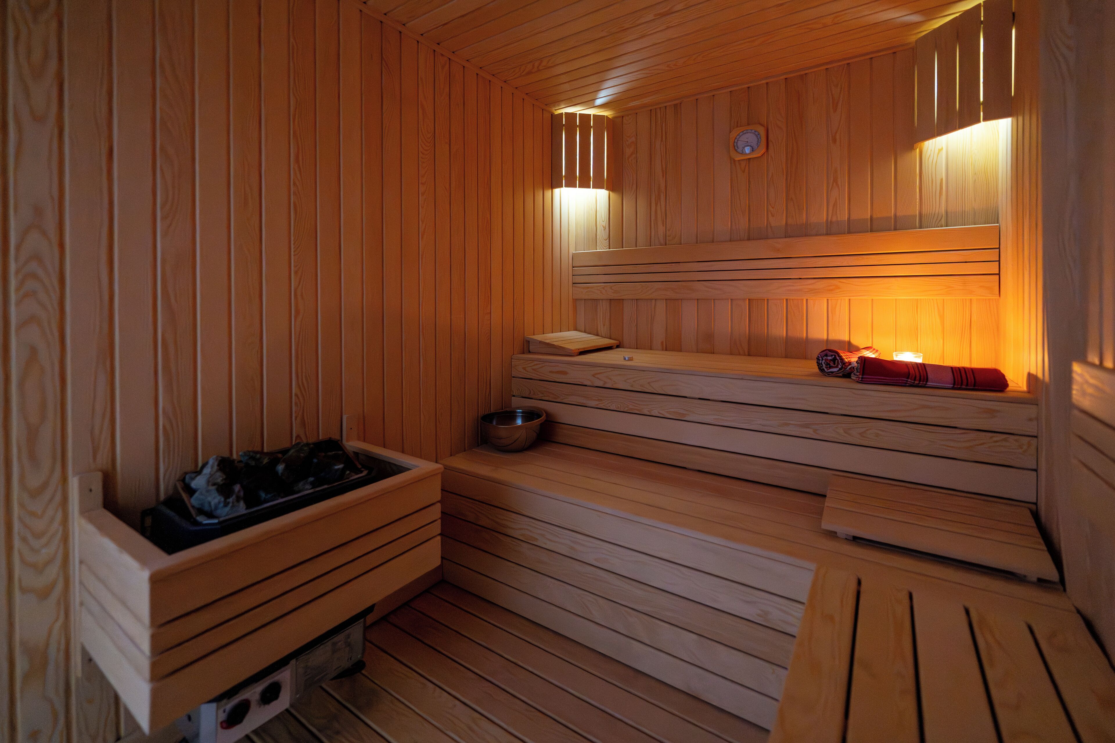 Uma sauna com bancos de madeira, um aquecedor para os bancos e um banco de madeira com uma toalha.