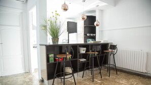 Uma cozinha moderna com bancada preta, quatro banquetas, uma planta em vaso e uma máquina de café.