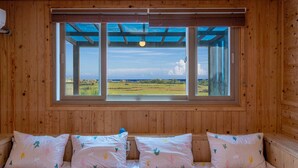 Quarto de cabana de madeira com uma grande janela com vista para a paisagem.