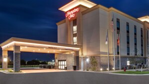 Um hotel Hampton Inn com design moderno, apresentando uma entrada bem iluminada e sinalização clara.