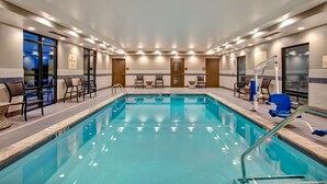 Piscina interior com sinal de proibição de saltos, cadeiras de descanso e sinal de proibição de saltos na parte inferior.
