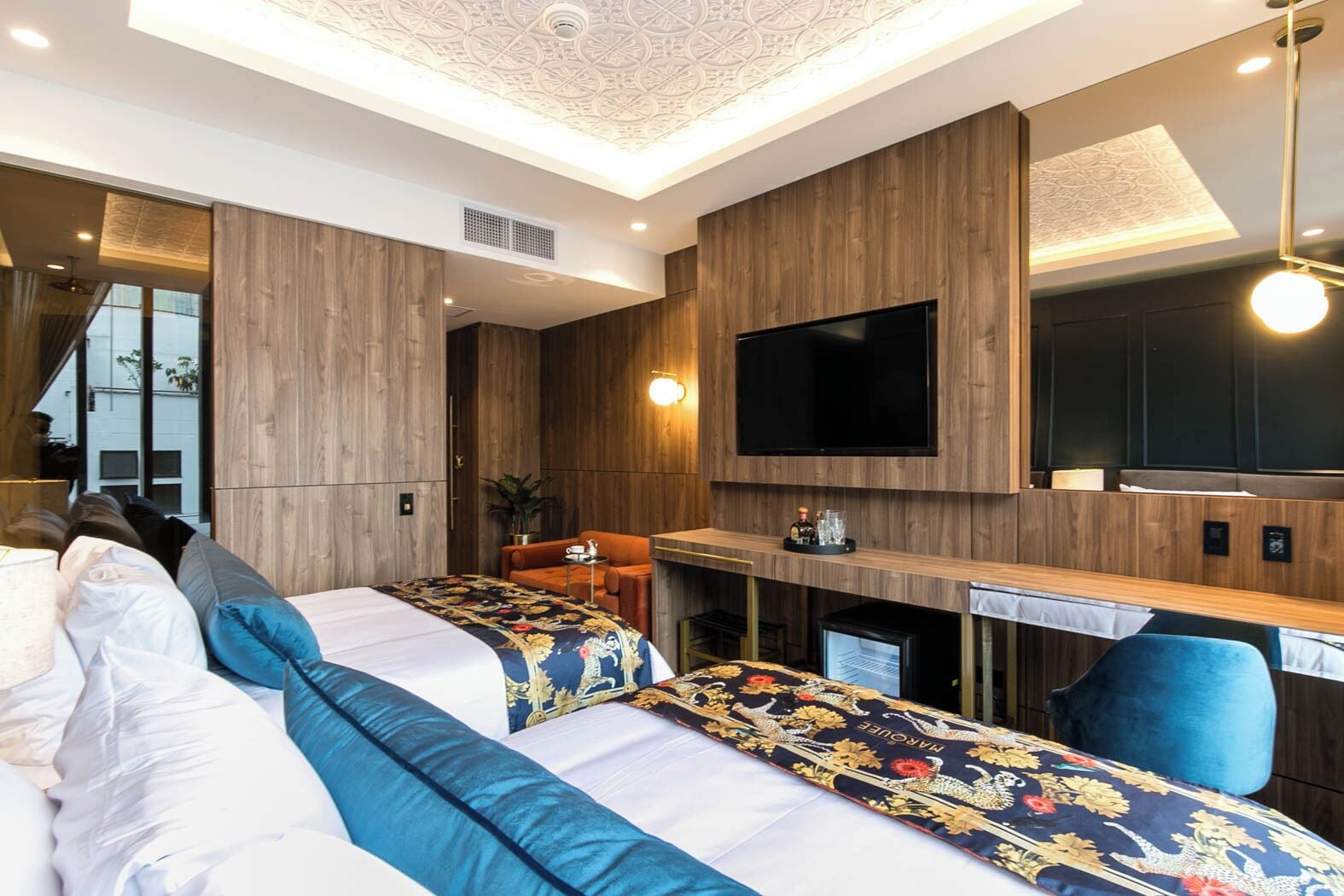 Quarto de hotel moderno com uma cama grande, uma escrivaninha e uma televisão.