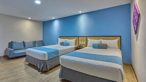 Quarto de hotel com duas camas, um sofá e chão de madeira.