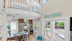 Uma cozinha espaçosa com área de jantar, varanda e uma placa com a inscrição "BEACH HOUSE".