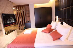 Quarto de hotel moderno com uma cama grande, televisão de tela plana e um painel de madeira.