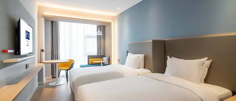 Quarto de hotel com duas camas, uma escrivaninha, uma cadeira e uma televisão.