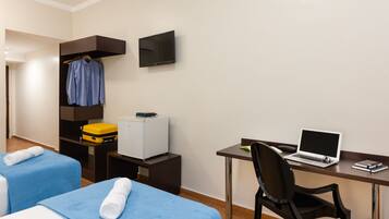 Quarto de hotel com duas camas, uma escrivaninha com um laptop, televisão e uma pequena geladeira.
