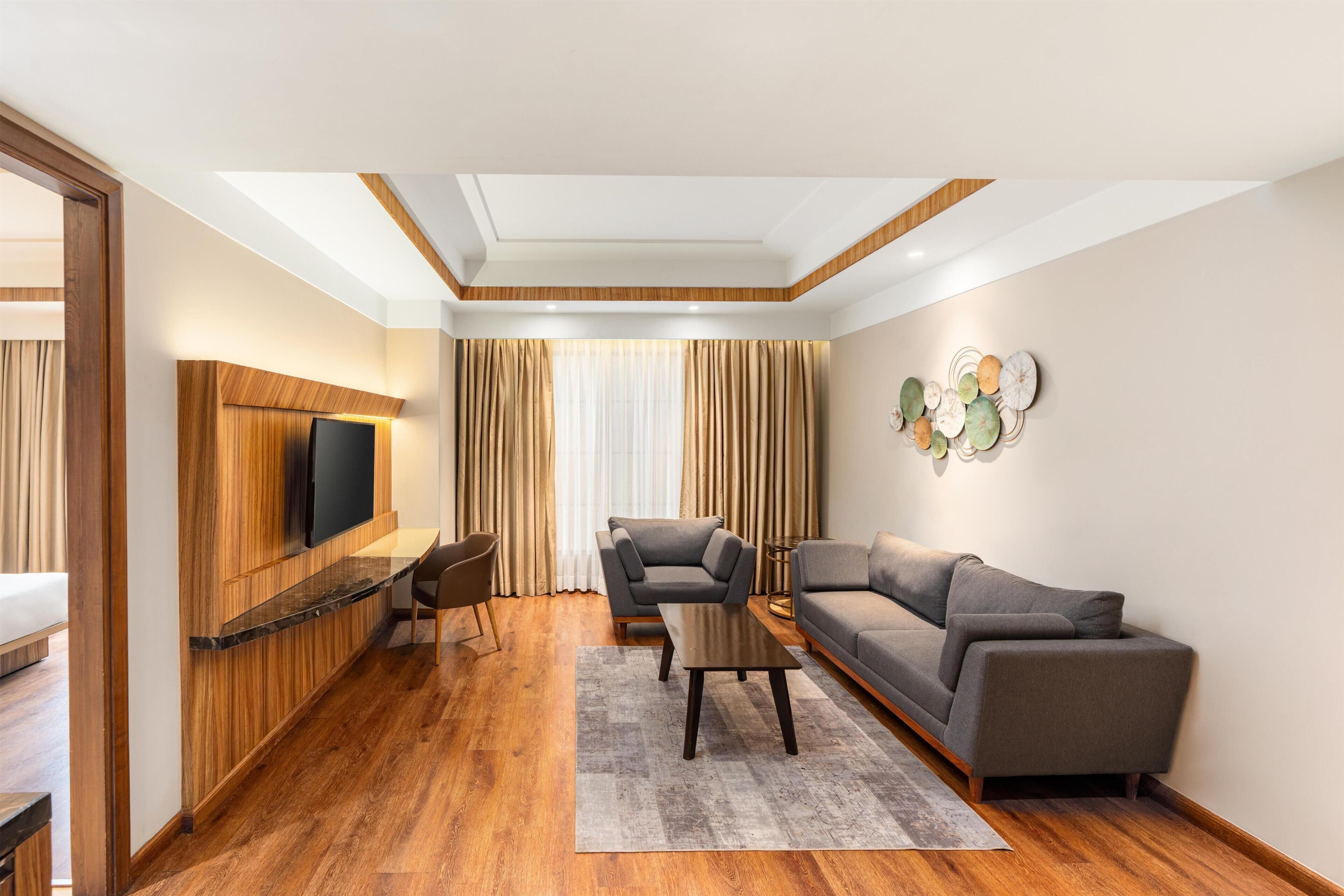 Uma sala de estar moderna com televisão de tela plana, sofá, mesa de centro e área de jantar com mesa e cadeiras de madeira.