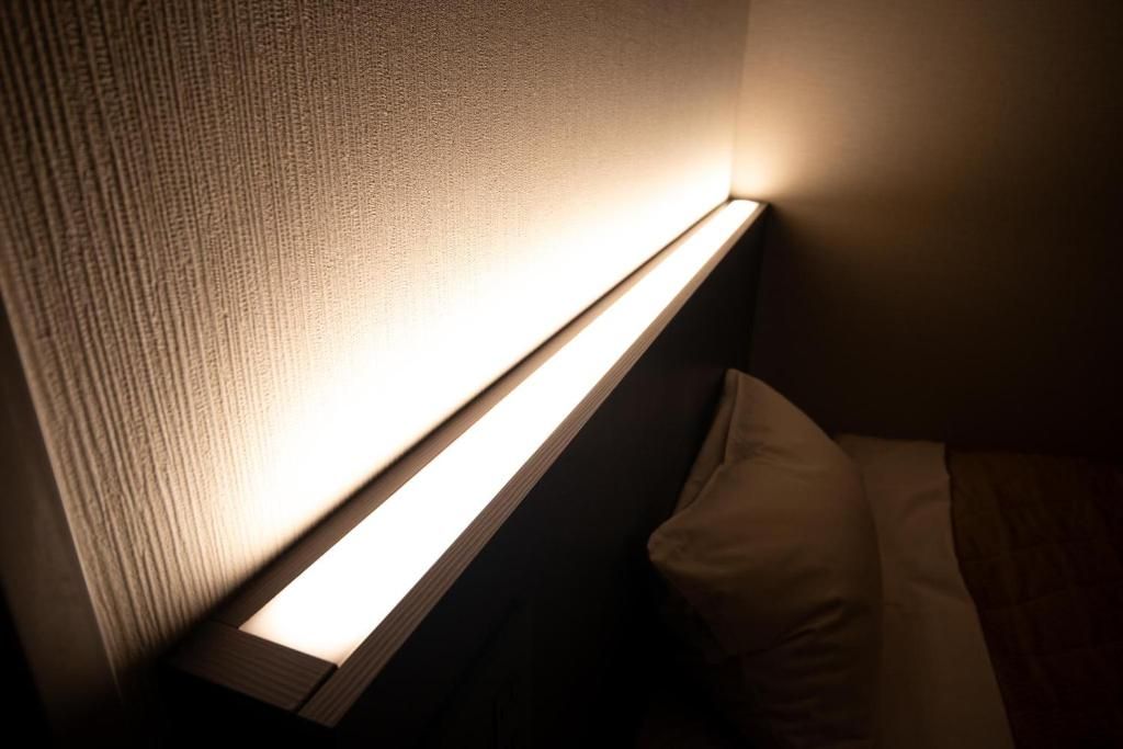 Uma luminária de cabeceira iluminando um canto do quarto.