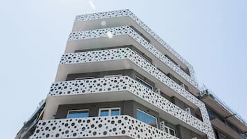 Edifício de vários andares com varandas e guarda-corpos de metal perfurado.