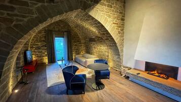 Um quarto acolhedor com paredes de pedra, lareira, sofá e mesa de jantar.