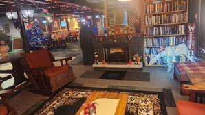 Uma sala de estar aconchegante com lareira, estante de livros e árvore de Natal.