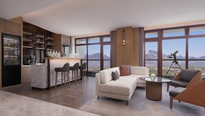 Uma sala de estar moderna com sofá, mesa de centro e área de bar com banquetas.