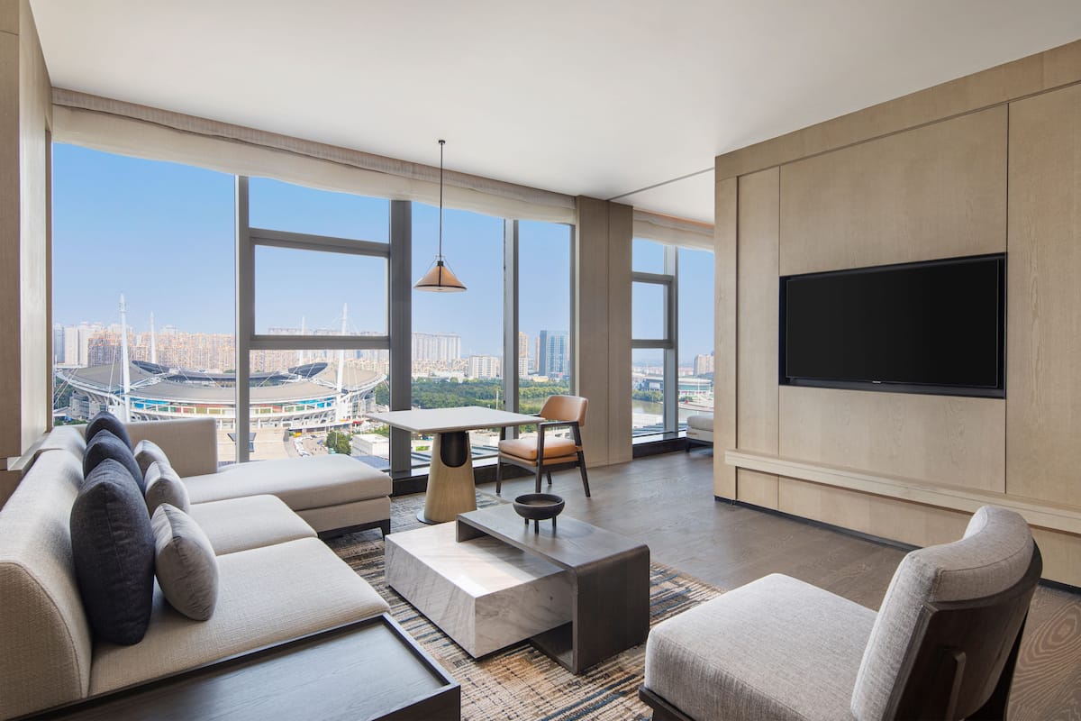 Uma sala de estar moderna com uma televisão grande, assentos confortáveis, uma área de jantar e vista para o horizonte da cidade.