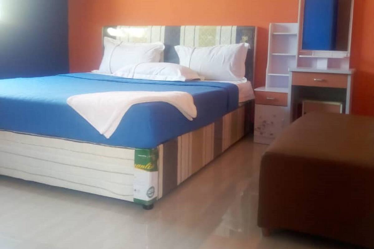 Quarto com cama, mesa de cabeceira, cômoda e espelho.