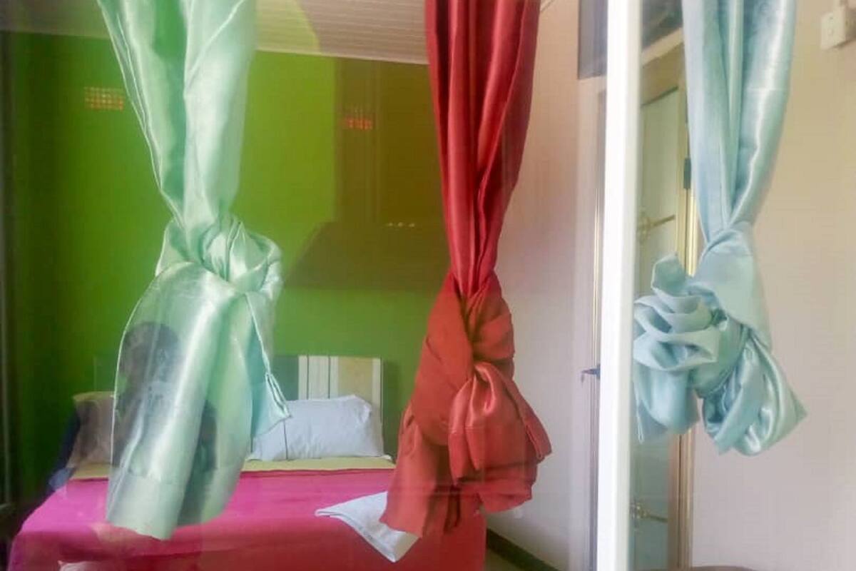 Um quarto com cama, cortinas e mesa de cabeceira.