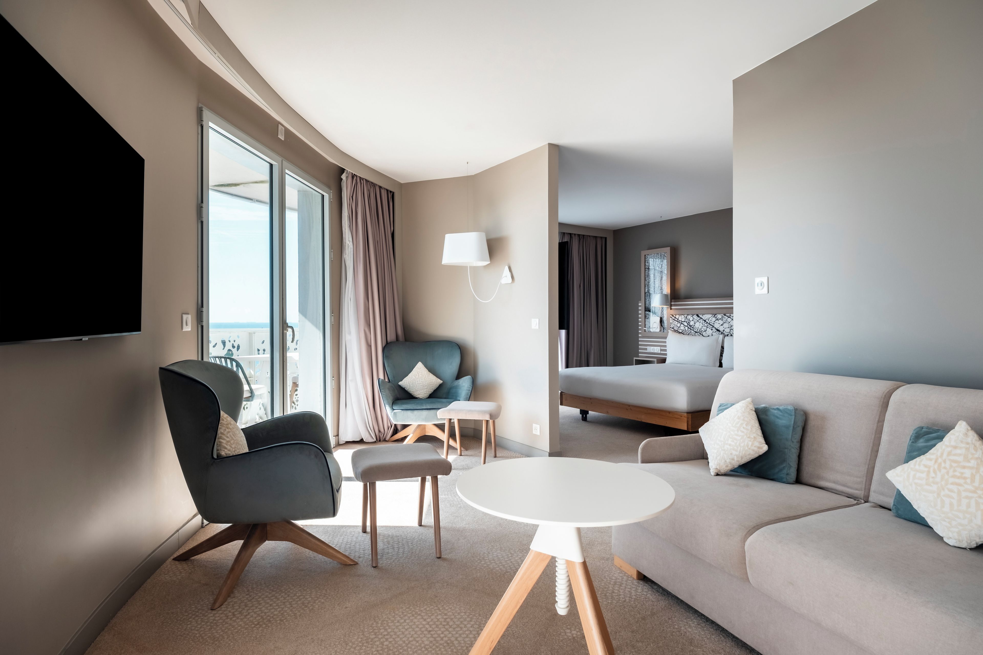 Quarto de hotel moderno com sofá, poltrona e uma pequena mesa.