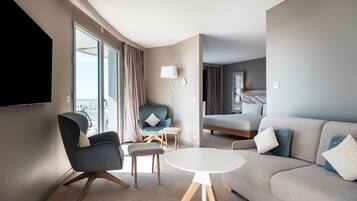 Quarto de hotel moderno com sofá, poltrona e uma pequena mesa.