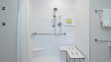 Um banheiro moderno com chuveiro, vaso sanitário e um pequeno nicho com artigos de higiene pessoal.