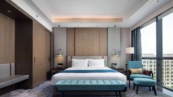 Quarto de hotel moderno com uma cama grande, área de estar, uma cadeira e vista para a cidade.