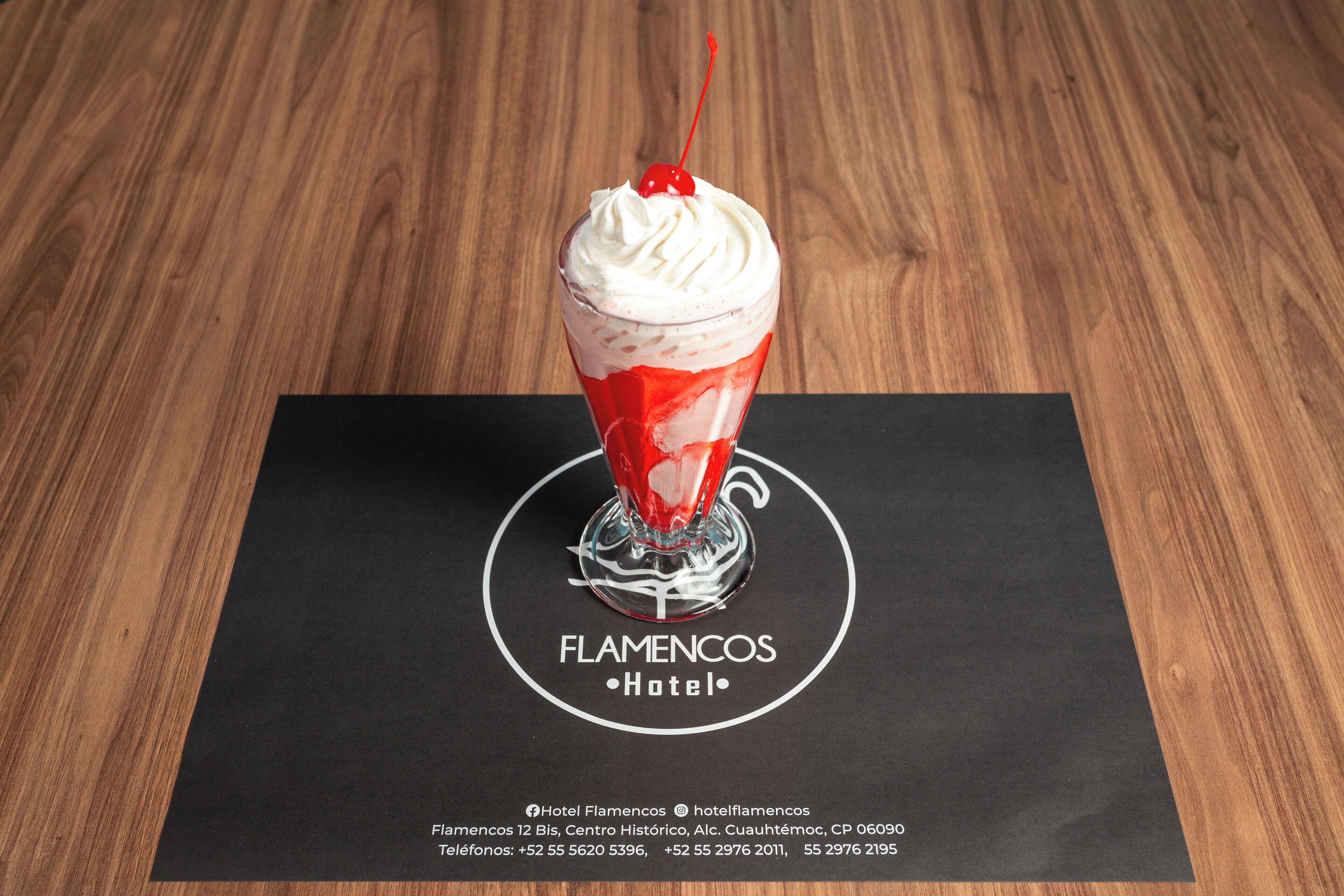 Sobremesa sobre um sousplat preto com o logotipo e informações de contato do Hotel Flamencos.