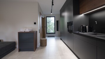 Uma cozinha moderna com forno embutido, máquina de café e uma janela grande que traz luz natural.
