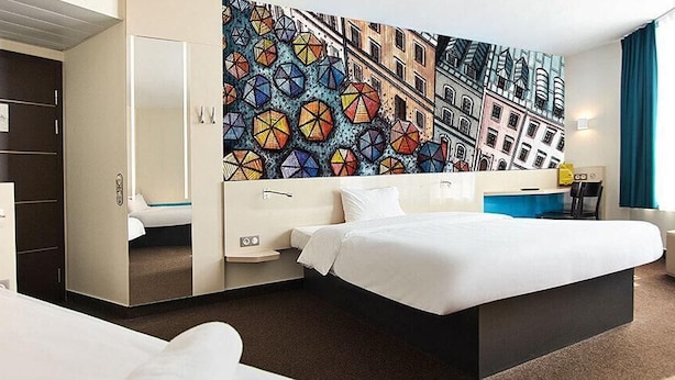 Quarto de hotel com uma cama grande, uma escrivaninha, uma cadeira e um guarda-roupa.